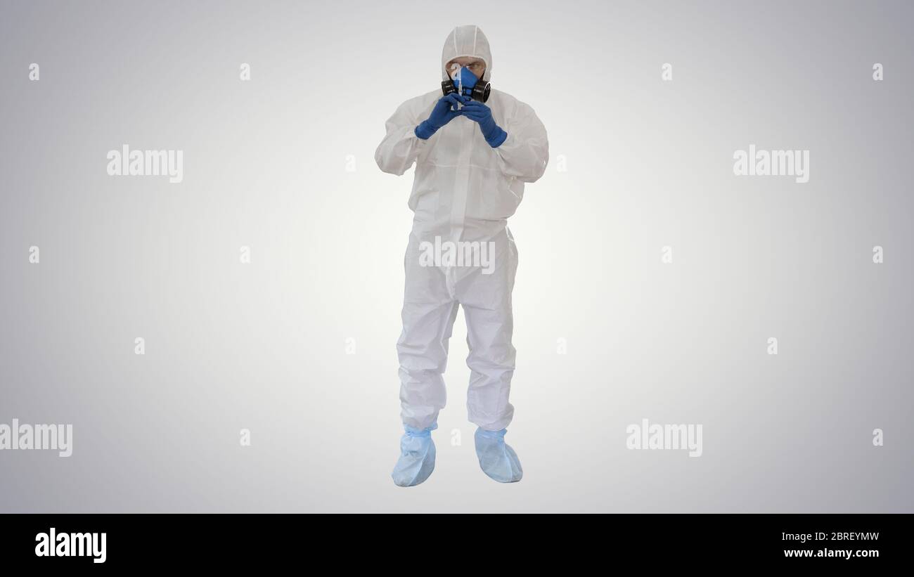 Doctor in hazmat protective with glasses and respirator uses syringe on ...