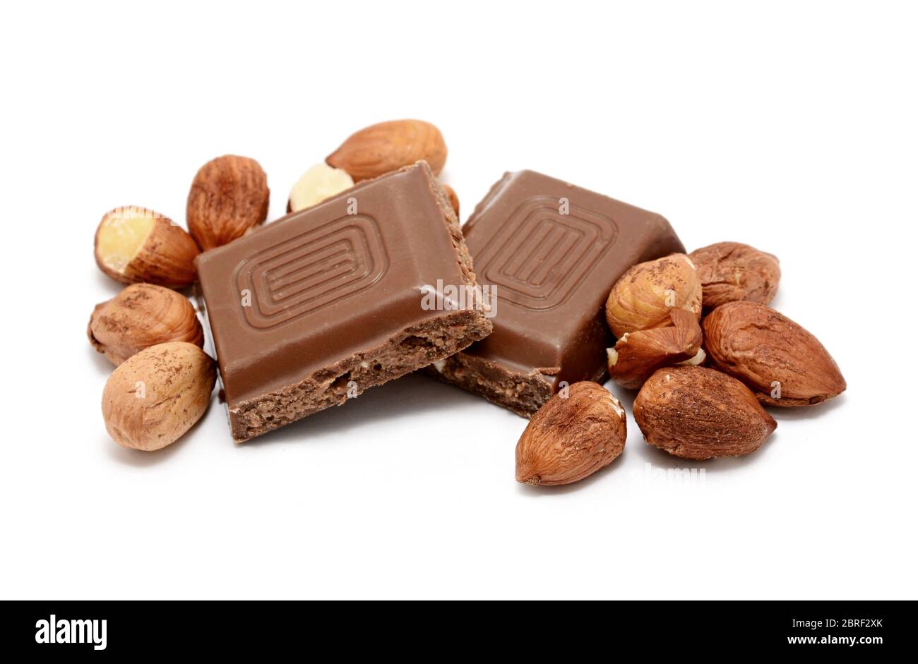Two squares of hazelnut milk chocolate bar with whole hazelnuts over ...
