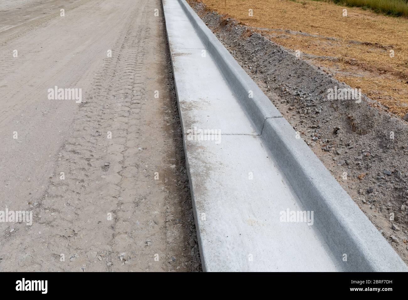 New roadway under construction, extruded concrete curb beside graded ...