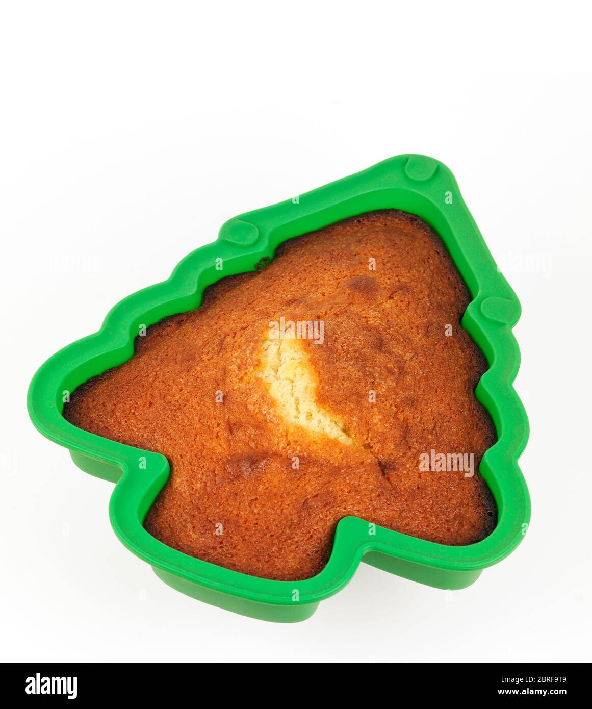 Christmas tree shaped sponge cake in oven tray on white background ...