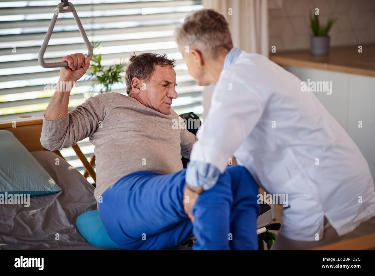 A healthcare worker helping paralysed senior patient in hospital Stock ...
