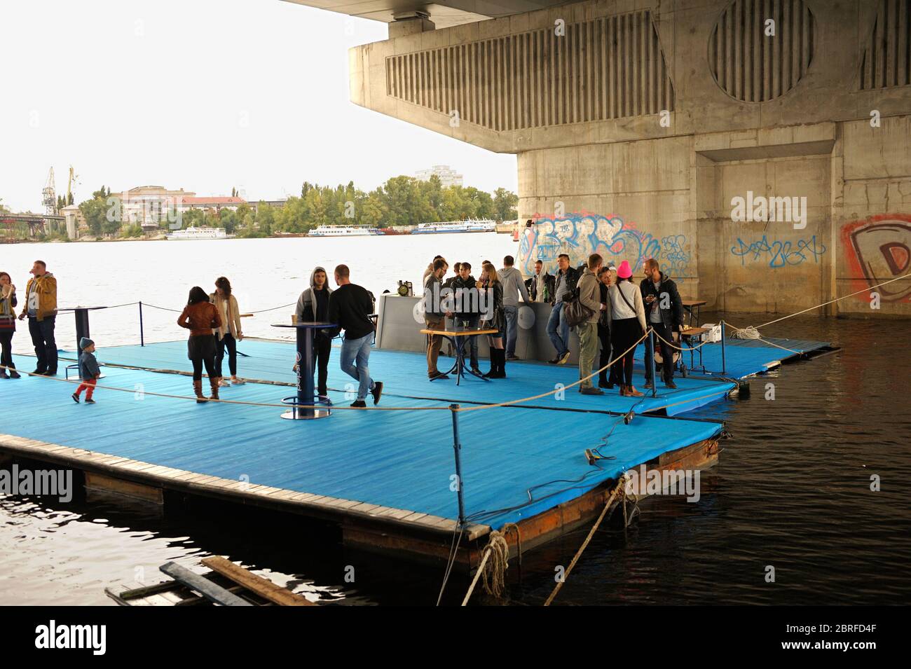 People eating in the floating outdoor restaurant set under bridge on ...