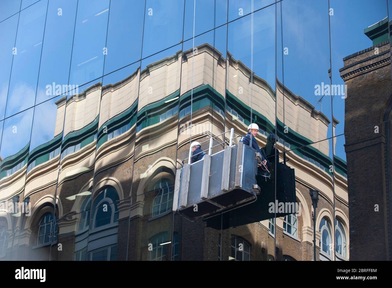 Two male window cleaners clean, and are reflected in, the outside glass ...