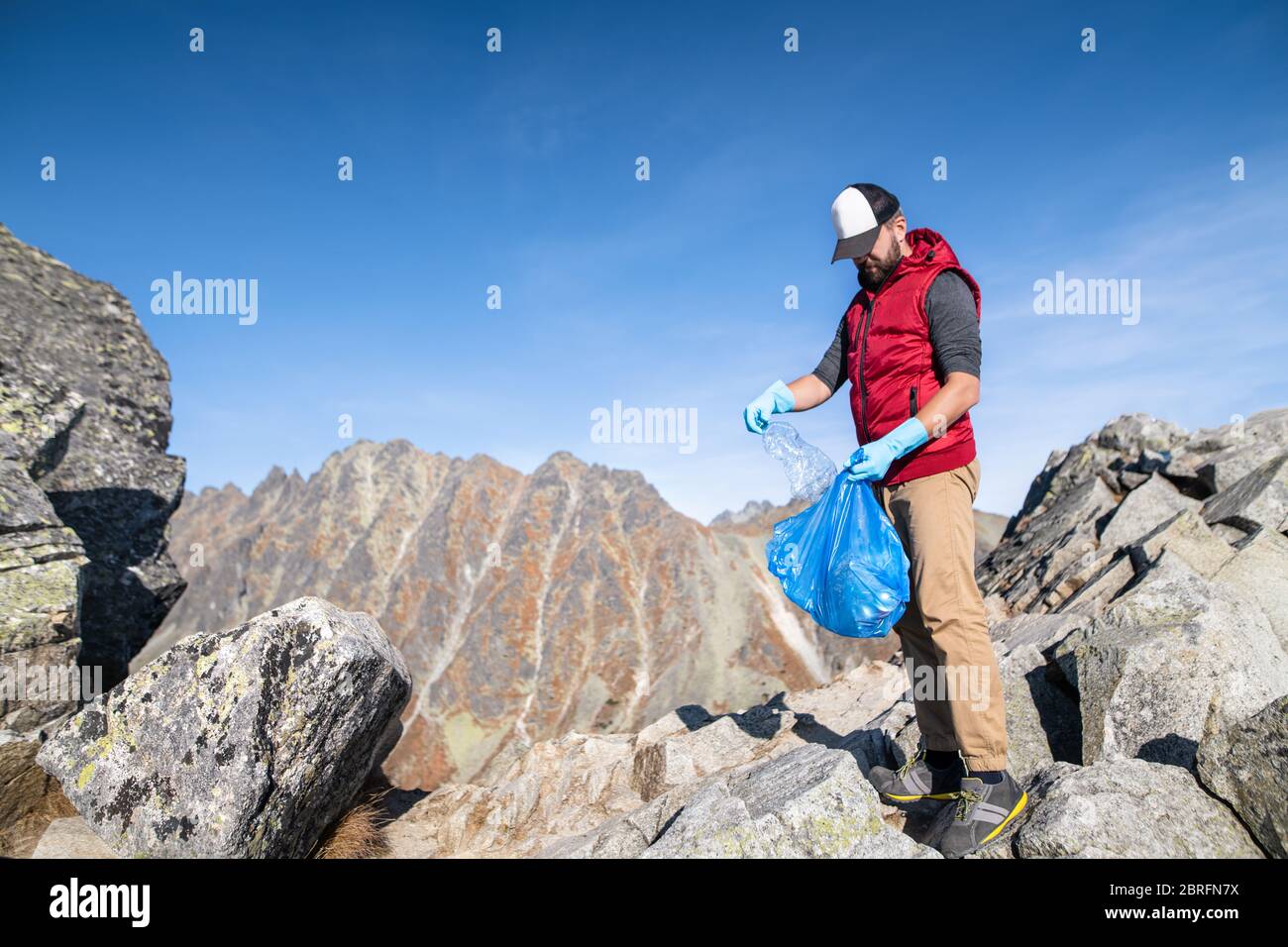 Man hiker picking up litter in nature in mountains, plogging concept ...