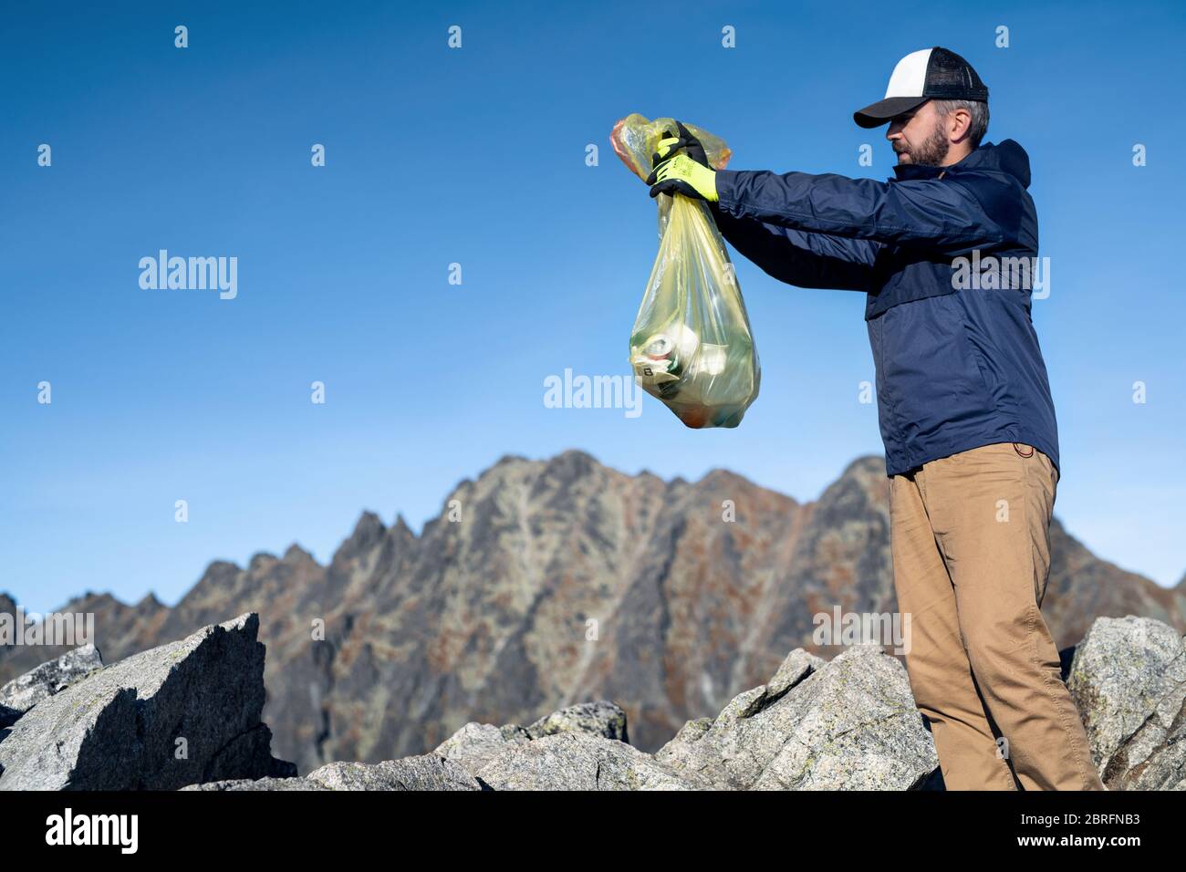 Man hiker picking up litter in nature in mountains, plogging concept ...