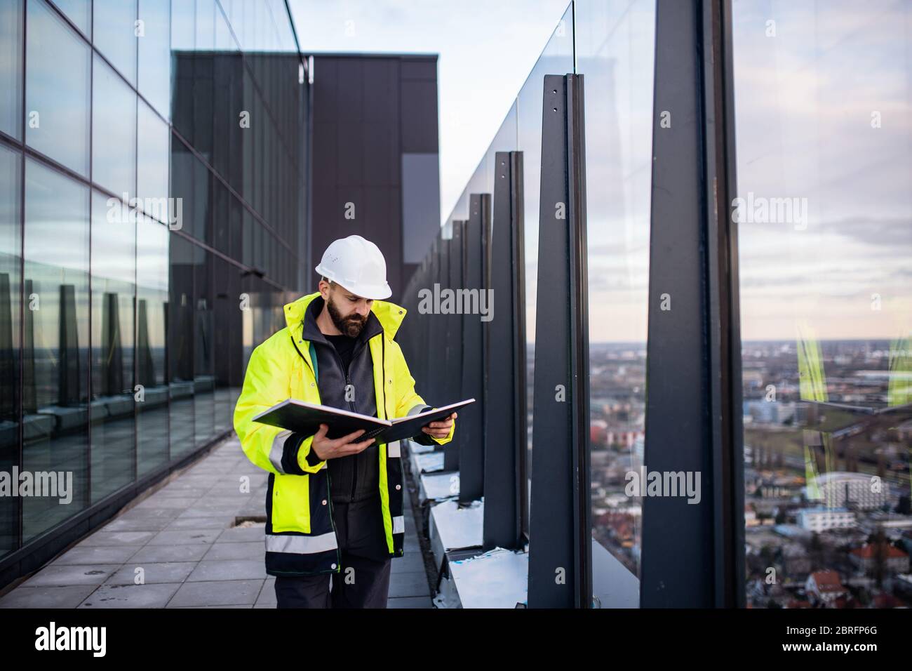 Man engineer standing on construction site, holding blueprints Stock ...