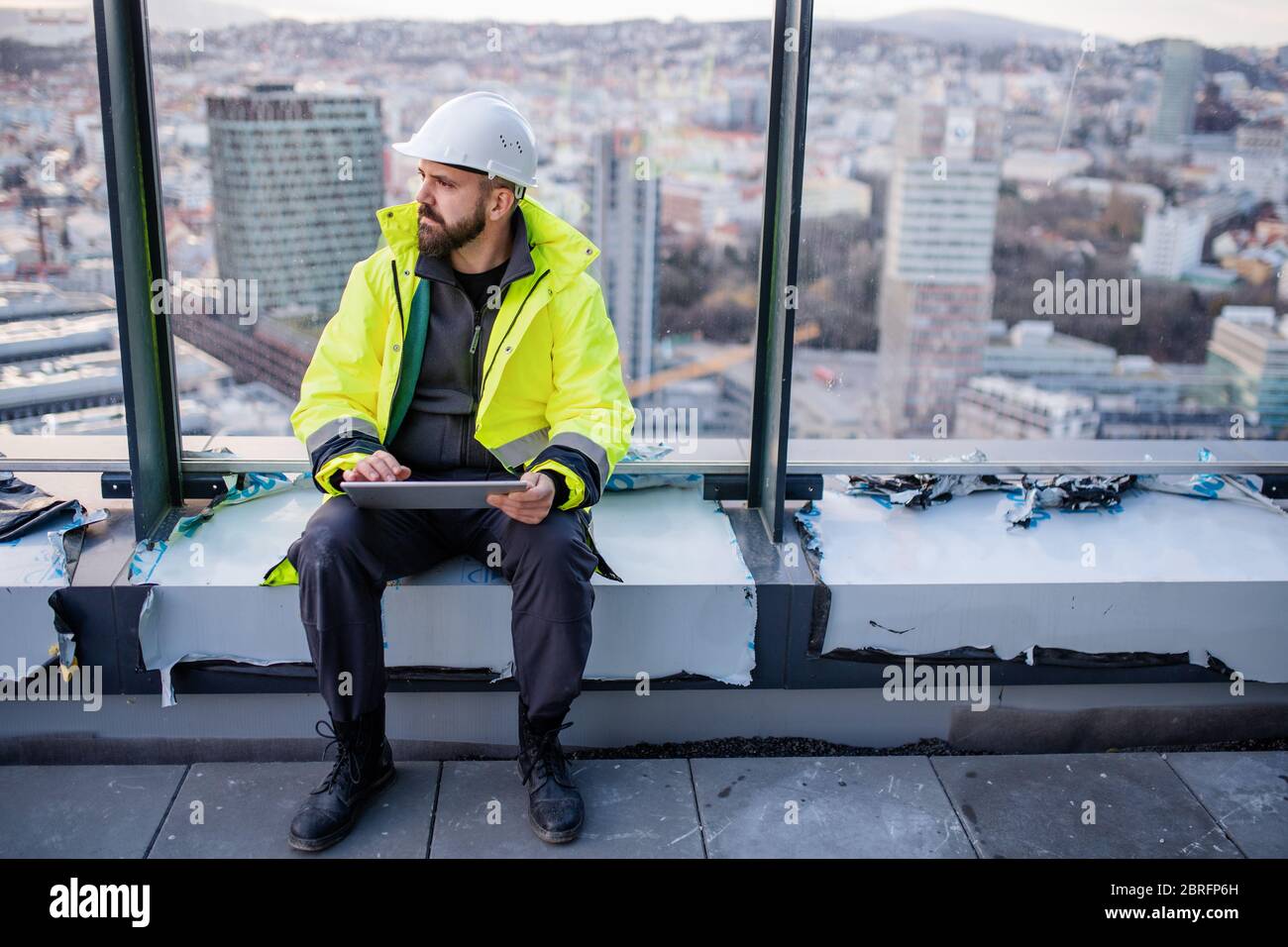 Man engineer sitting on construction site, holding tablet Stock Photo ...