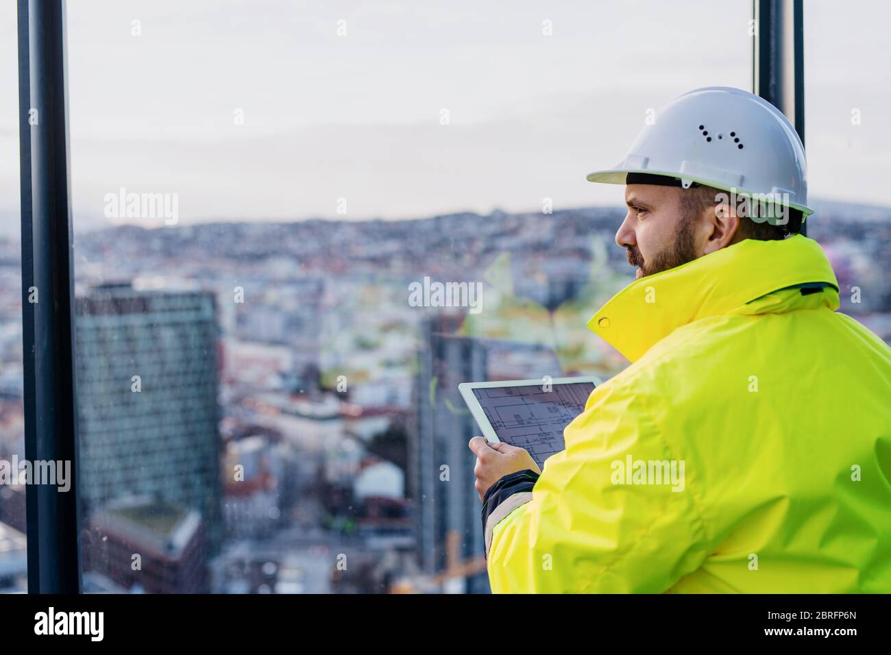 Man engineer standing on construction site, holding tablet with ...
