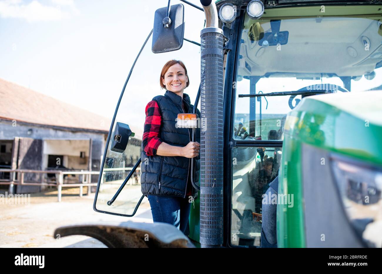 Woman worker standing by tractor on diary farm, agriculture industry ...