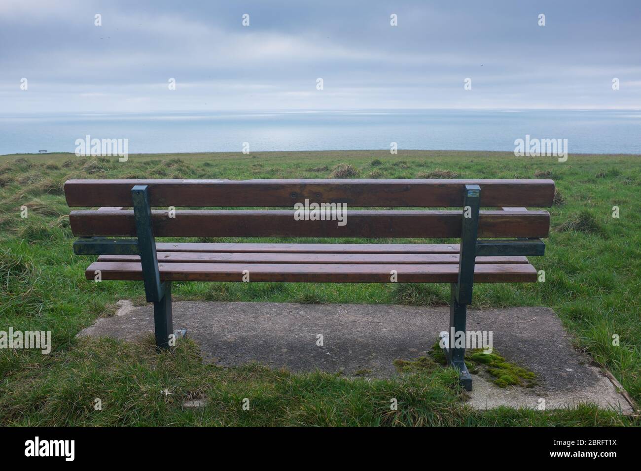 An unoccupied park bench on the coast with a view out to the sea in the ...