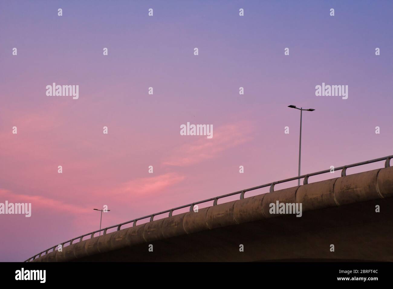 Highway from below with a couple of streetlights and pink sky at dawn ...
