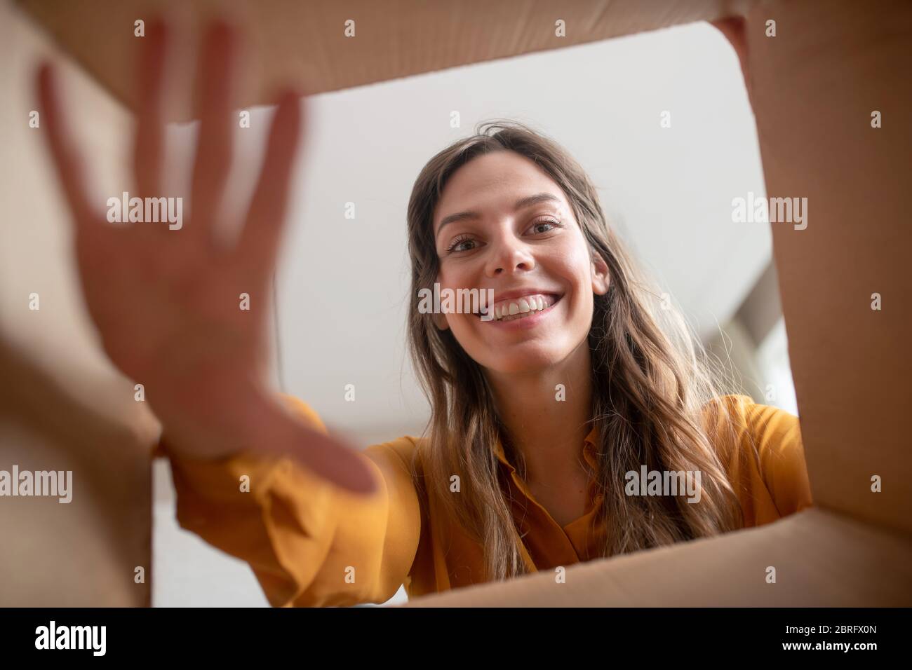Smiling young girl opening the box and stretching her hand Stock Photo ...