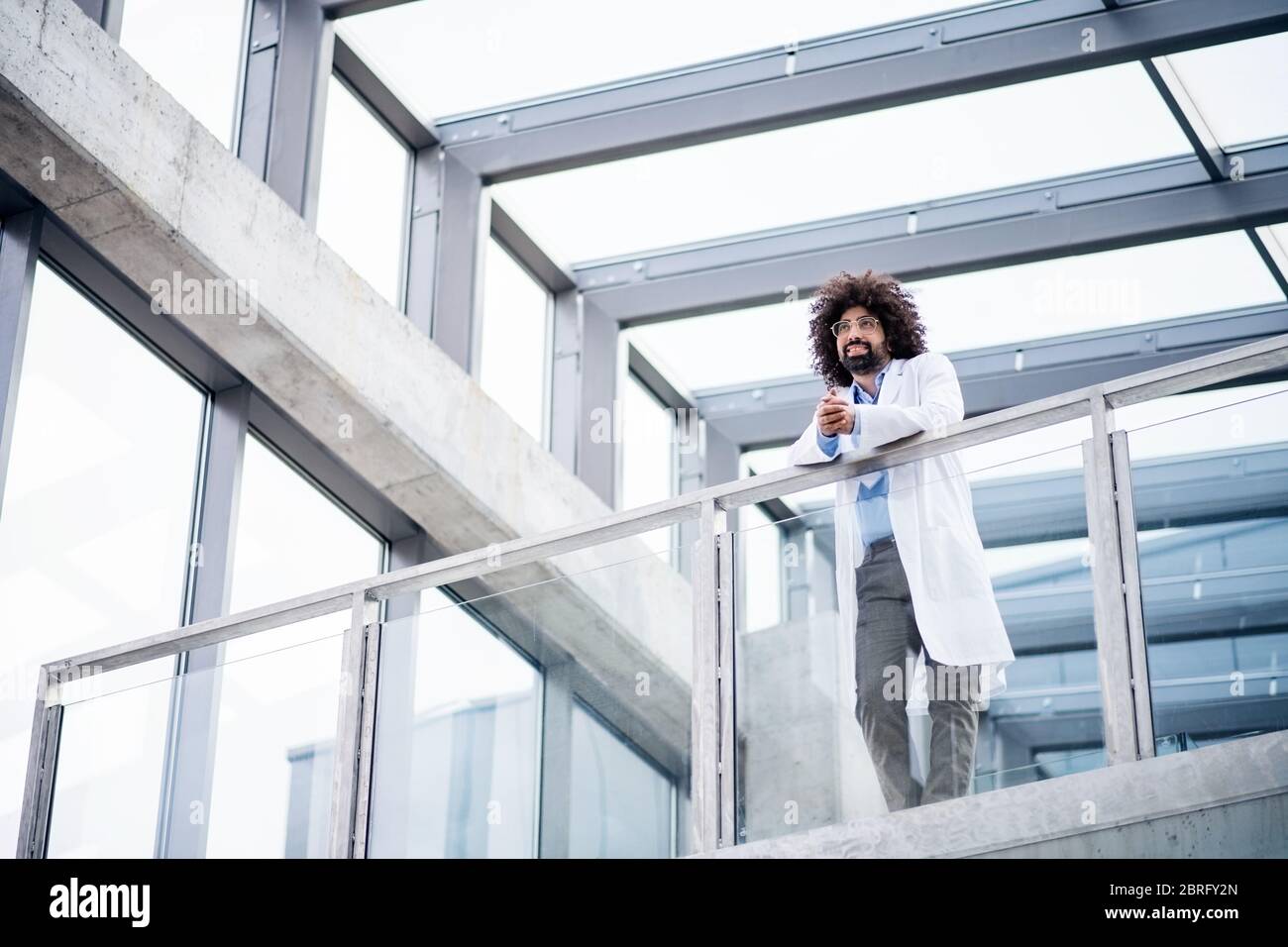 Portrait of male doctor standing on corridor, leaning on railing Stock ...
