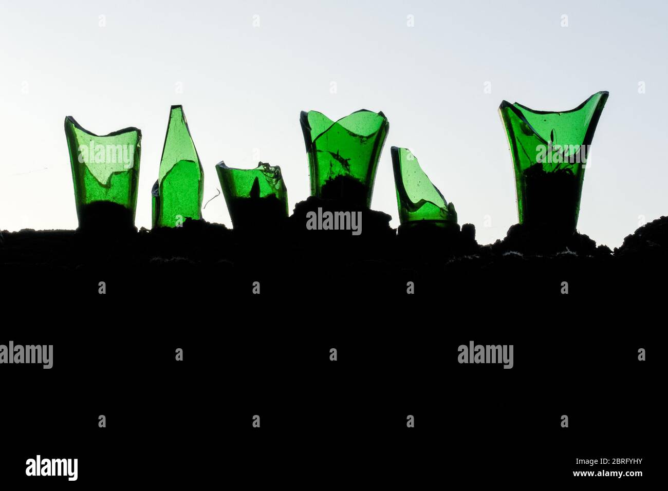 Broken bottles, glass shards on top of a wall Stock Photo - Alamy