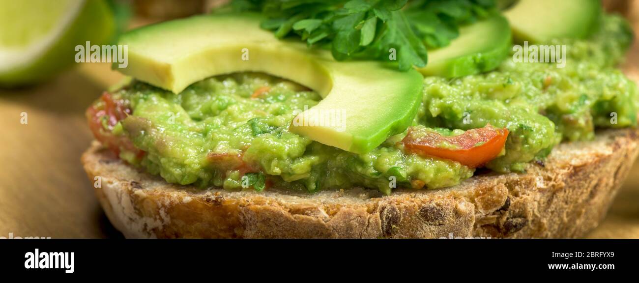 Slice of bread with guacamole made from avocado, tomato, lime, poarsley ...