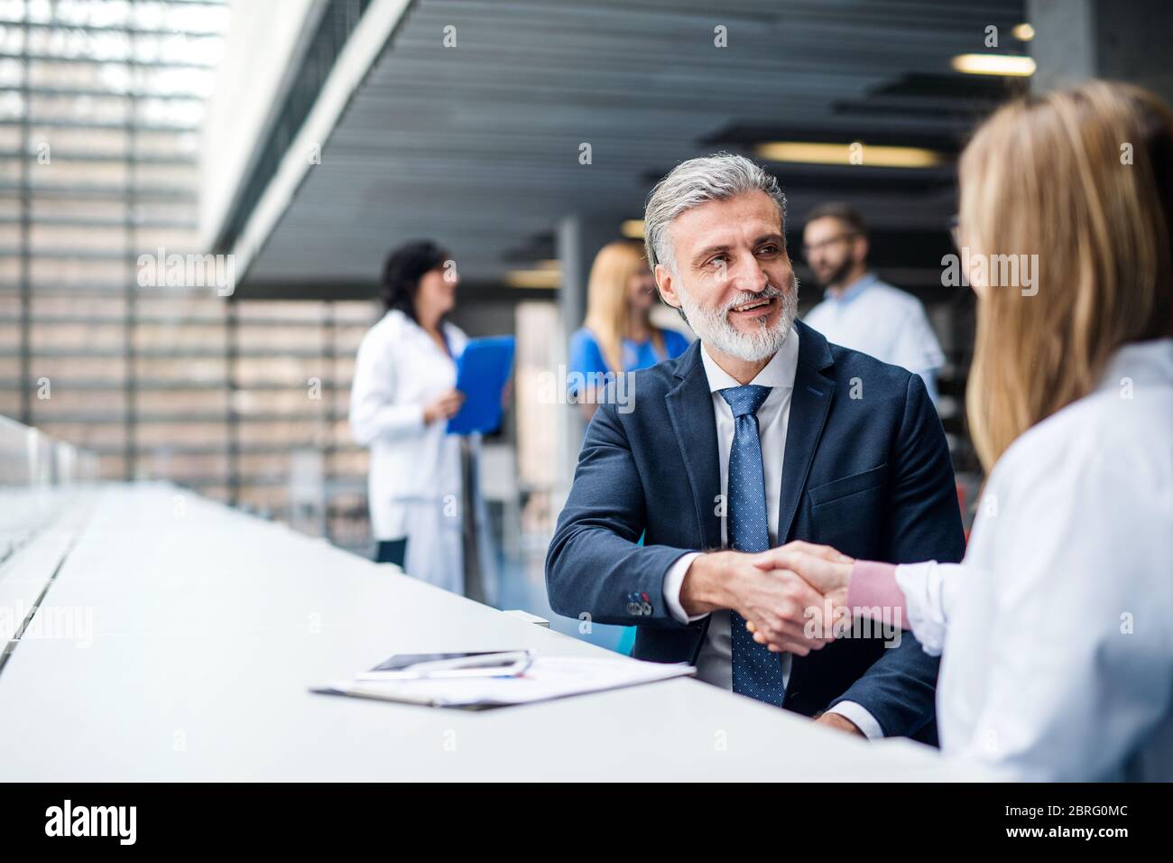 Doctors talking to pharmaceutical sales representative, shaking hands ...