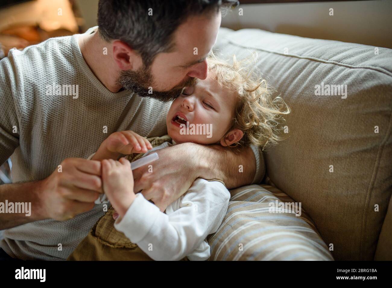 Father with small sick crying toddler daughter indoors at home Stock ...