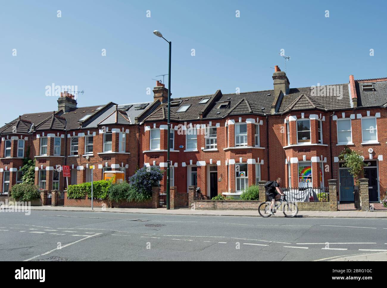 male cyclist passes a terrace of well maintained victorian houses in ...