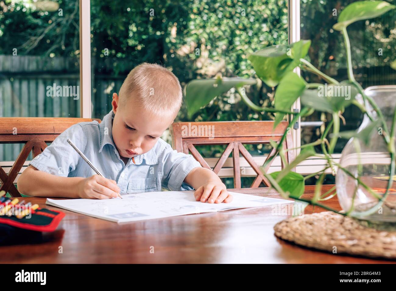 Little Child drawing in a textbook at home, a boy holding pen and ...