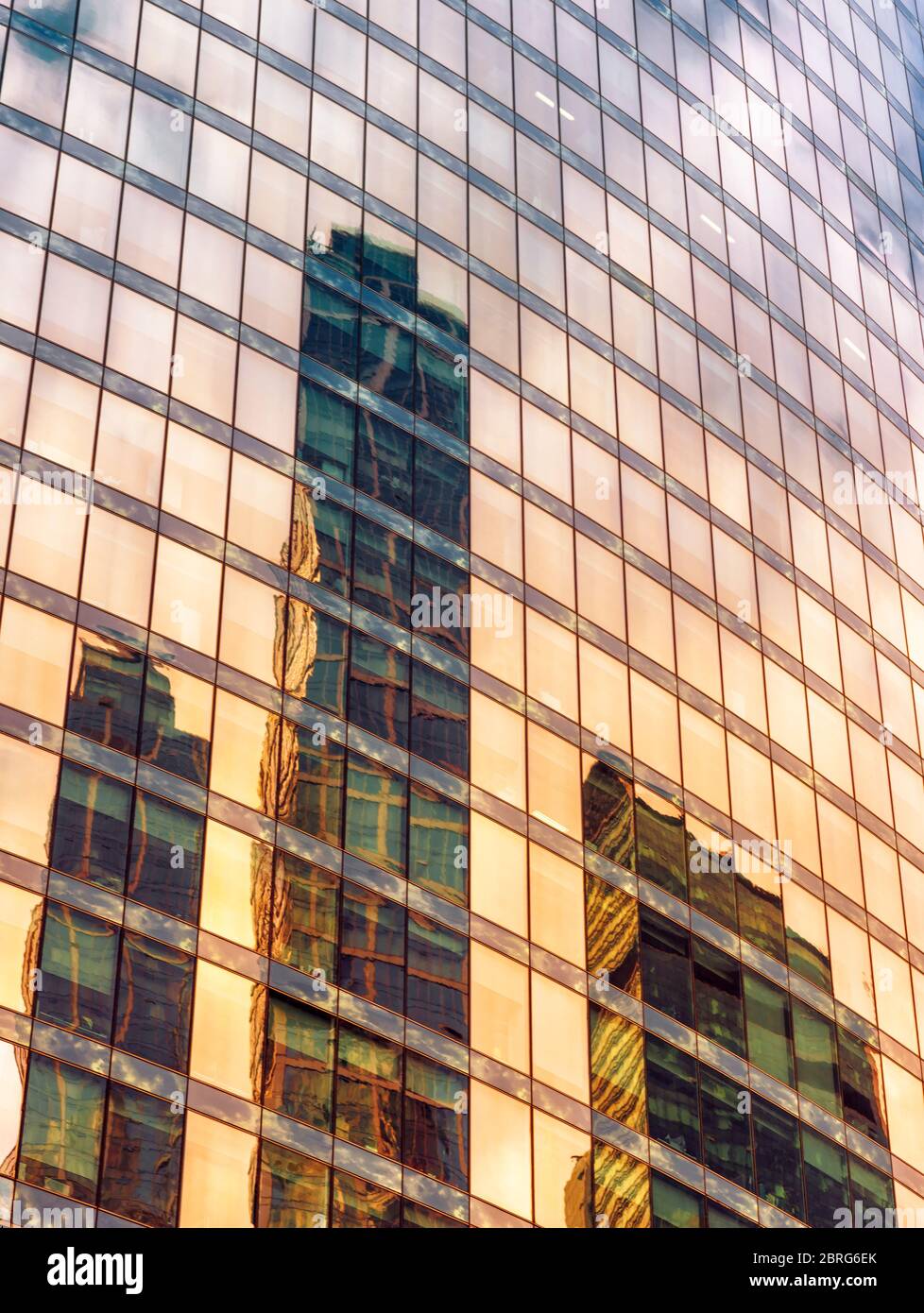 The sky and buildings are reflected in a modern skyscraper at sunset ...
