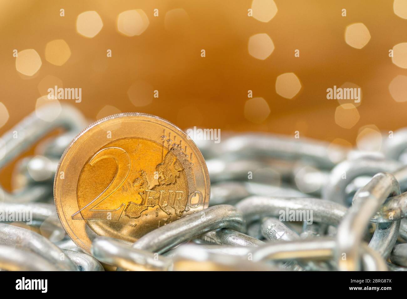 Two Euros Coin with a metal chain on a gold background Stock Photo - Alamy