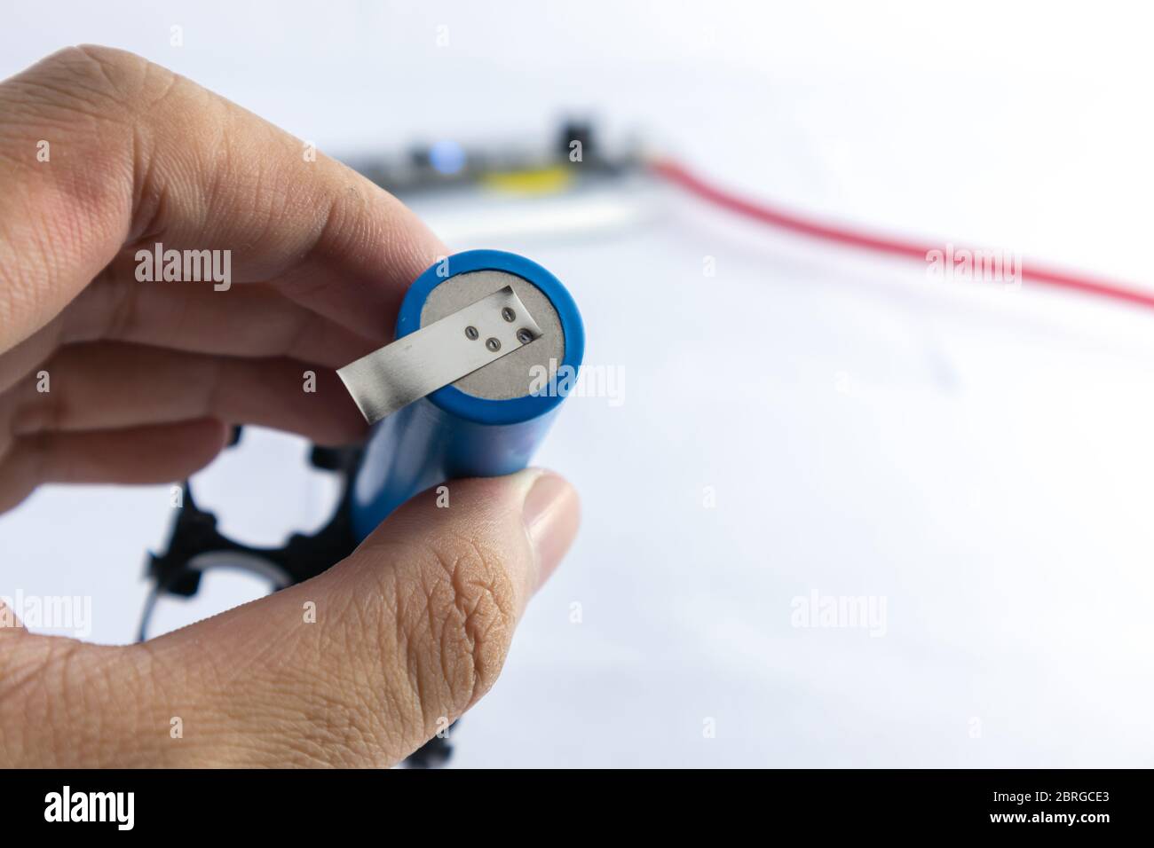 Spot welding blue lithium ion battery on hand with blurred background ...