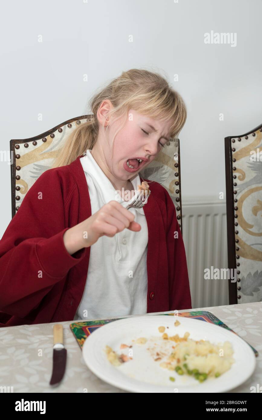young girl eating food that she does not like Stock Photo - Alamy