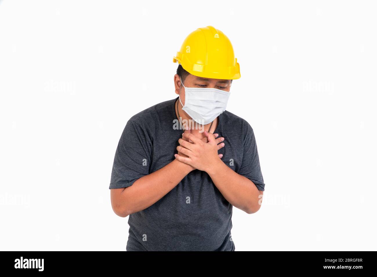 Male worker wearing a helmet and face mask and Coughing and pain and in ...