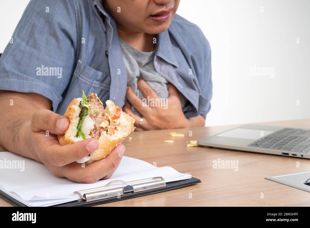 Asian man working and eating a burger on the office desk and heart ...