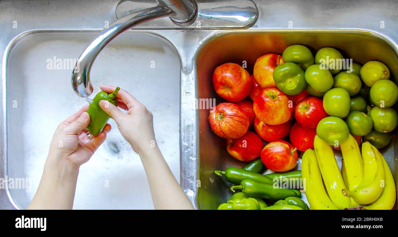 Washing vegetables and fruits on a sing with running water and soap ...