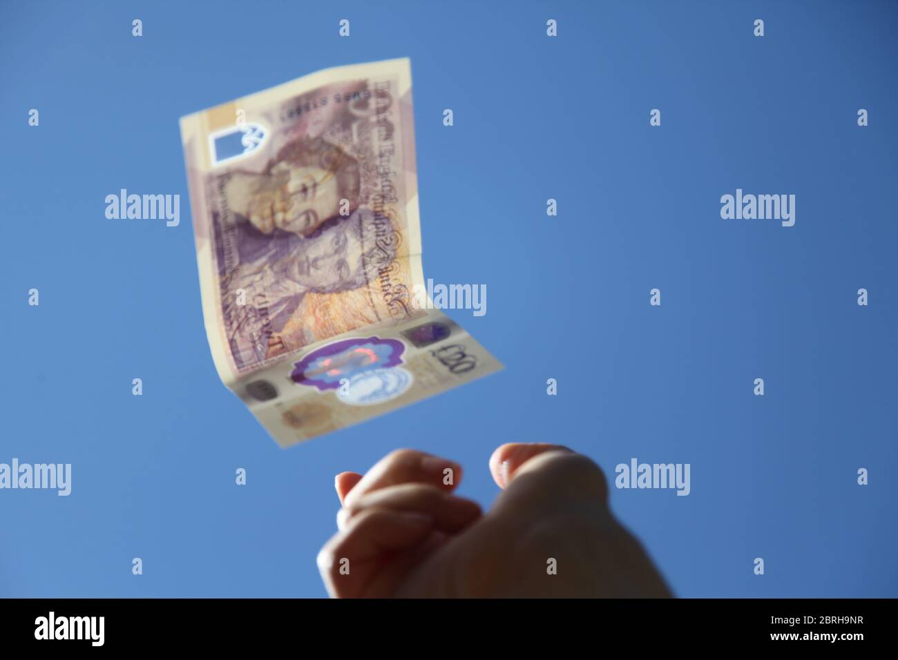 £20 note blows out of hand in the wind against blue sky, William Turner ...