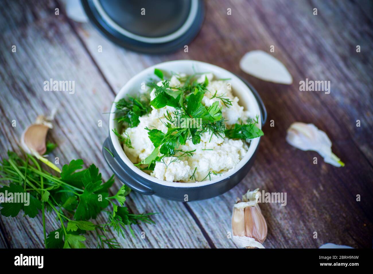 salted homemade cottage cheese with garlic and herbs in a bowl Stock ...