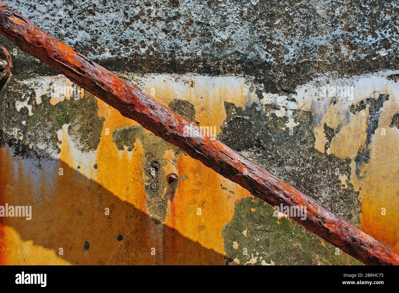 Old handrail attached to exterior weathered wall covered in rust stains ...