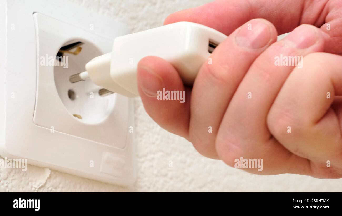 Insert the charger into a power outlet. Close up Stock Photo - Alamy