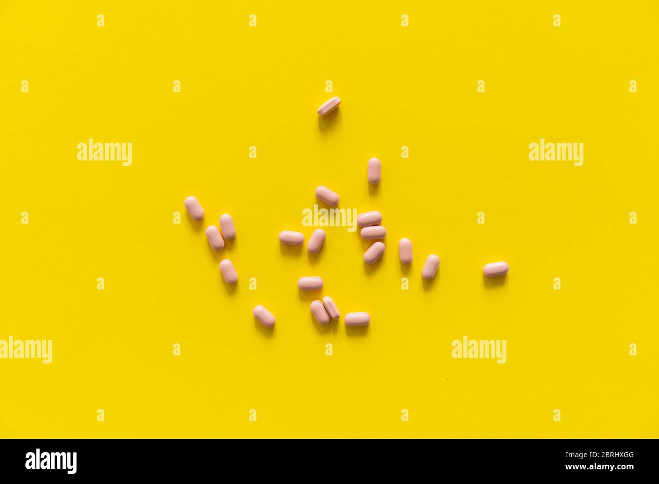 Pink pills on yellow background. Medicine, medication, painkillers ...