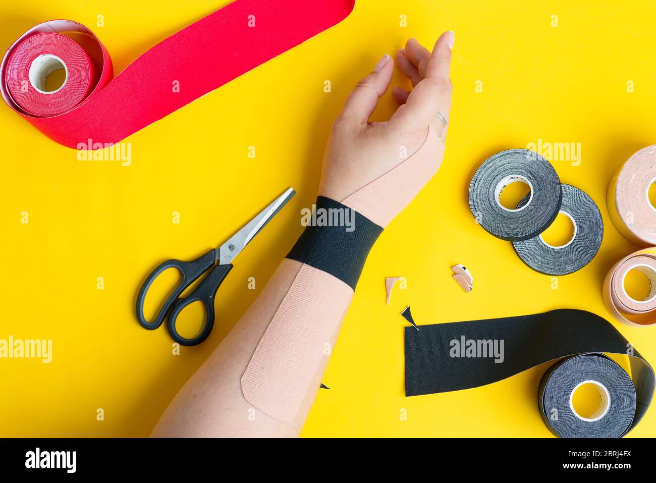 Kinesiology taping treatment with beige and black tape on female ...