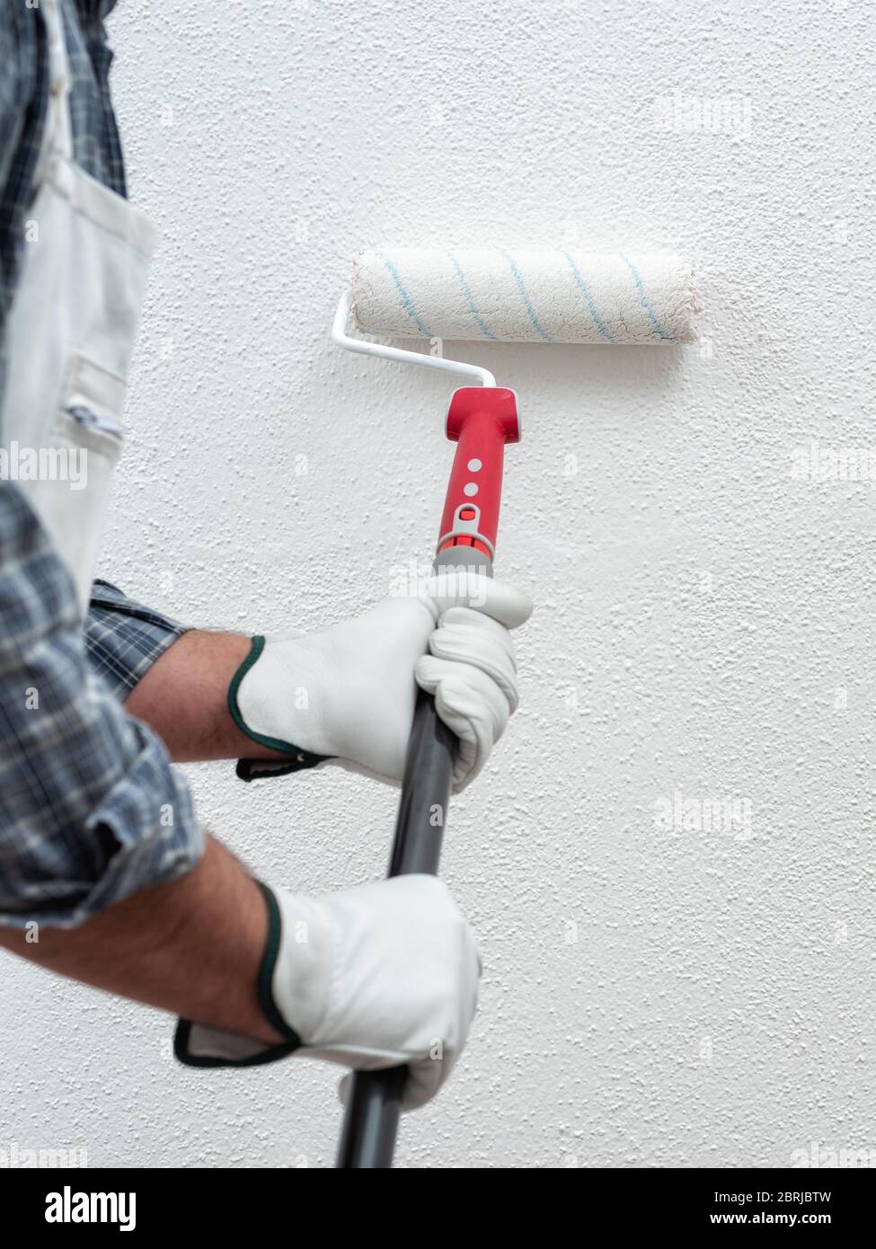 Caucasian house painter worker in white work overalls and with ...
