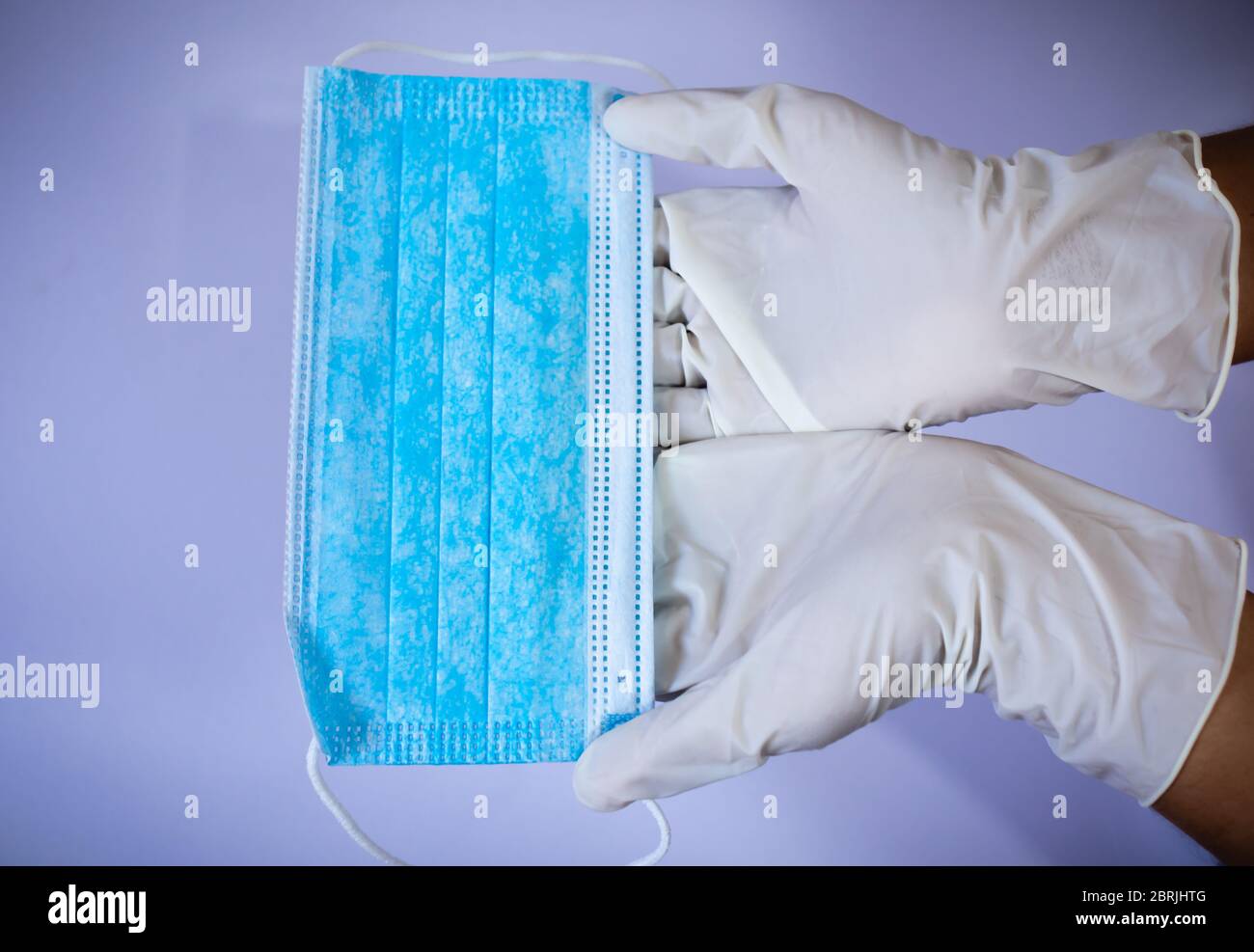 Medical face mask holding in both hands with gloves Stock Photo - Alamy