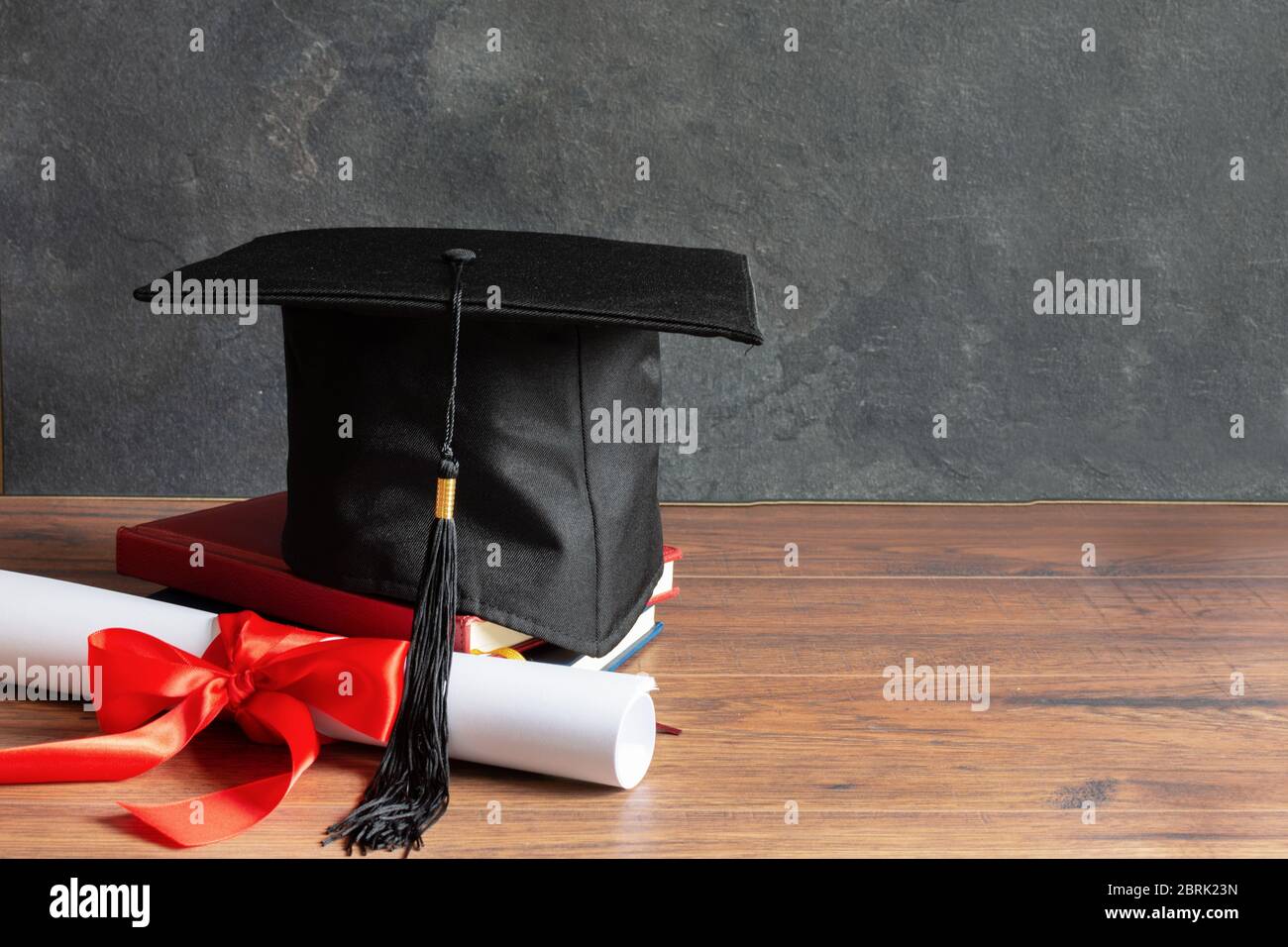 Academic cap and graduation diploma scroll and tied with red ribbon on ...