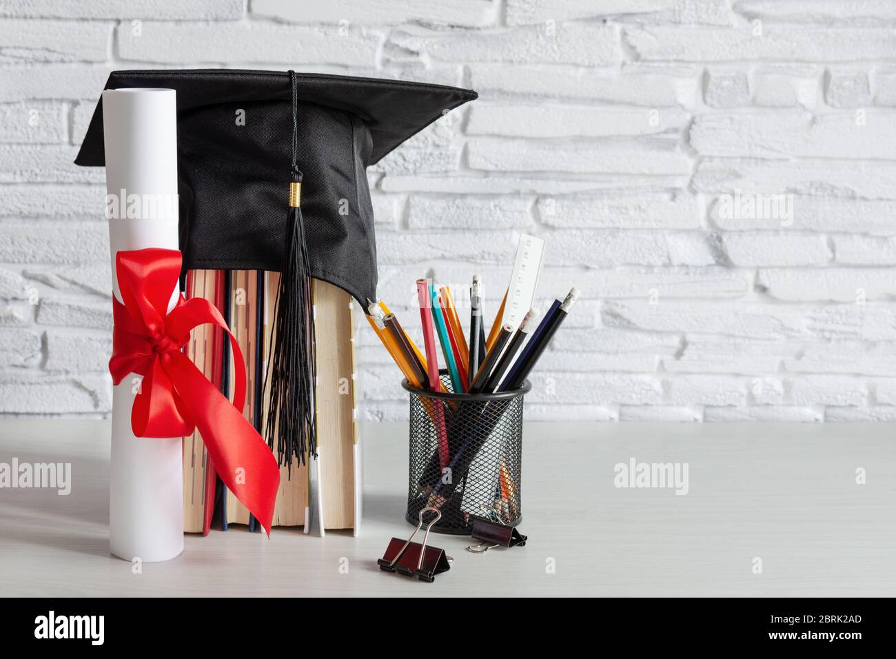 Academic cap and graduation diploma scroll and tied with red ribbon on ...
