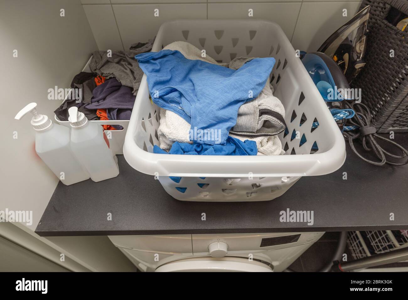 Interior view of laundry cabinet. Basket with clean clothes and iron ...