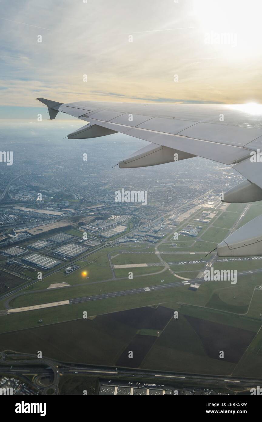 View over the clouds from the porthole of an airplane with plane wing ...