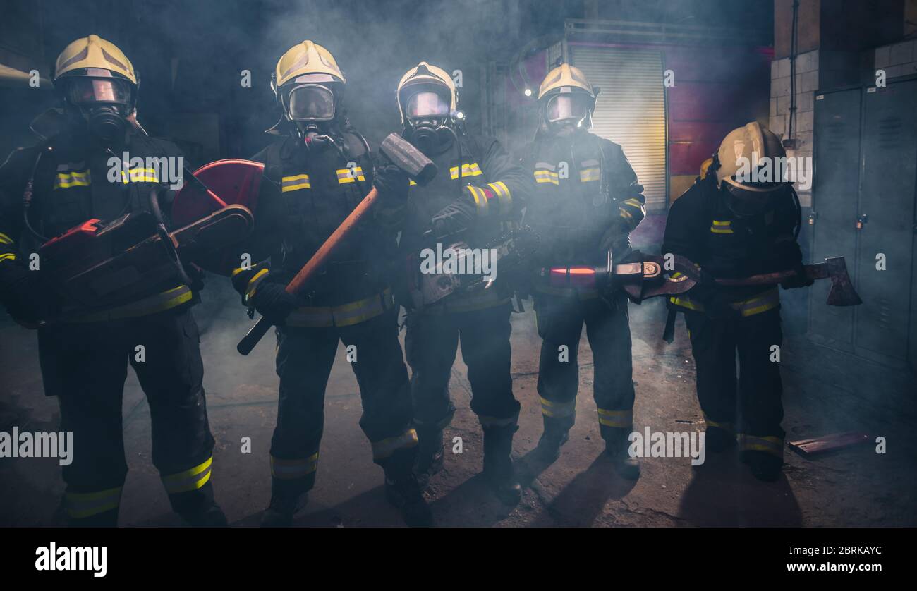 Group of firefighters with chainsaw and sledge hammer practicing in the ...