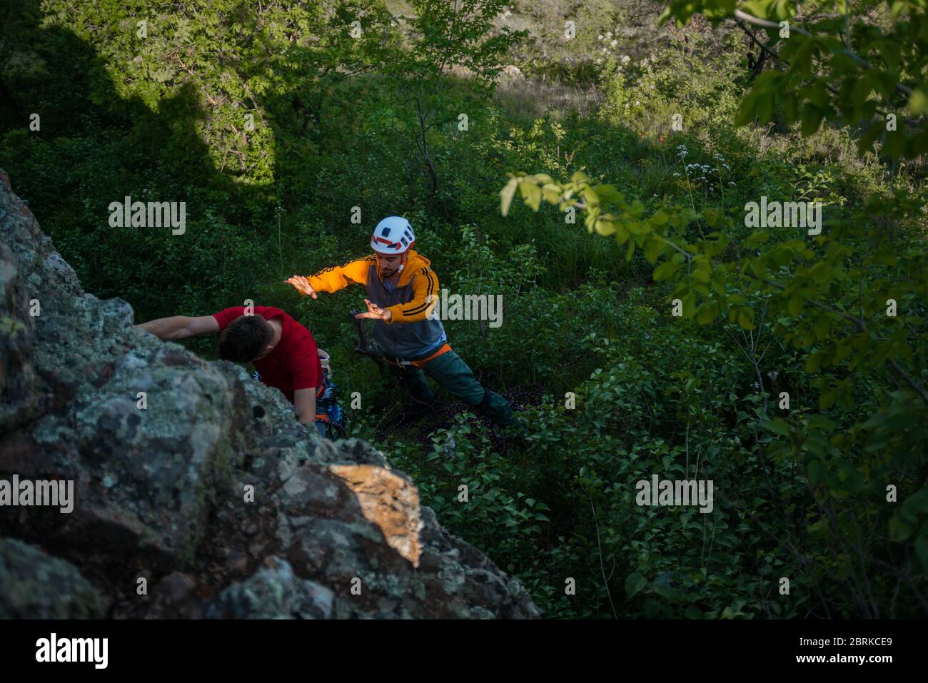 Strong man climbs the mountain with the support of his friends Stock ...