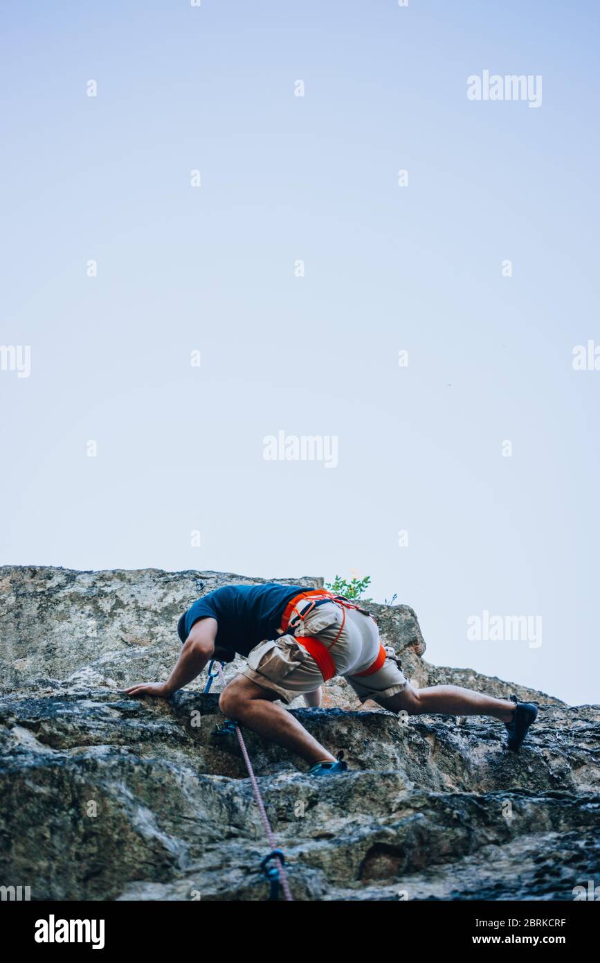 Brave and confident rock climber makes hard move on her climbing rout ...