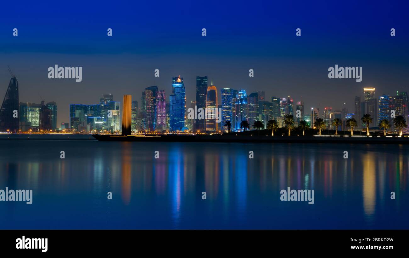 Doha skyline during the evening with colorful towers around Stock Photo ...