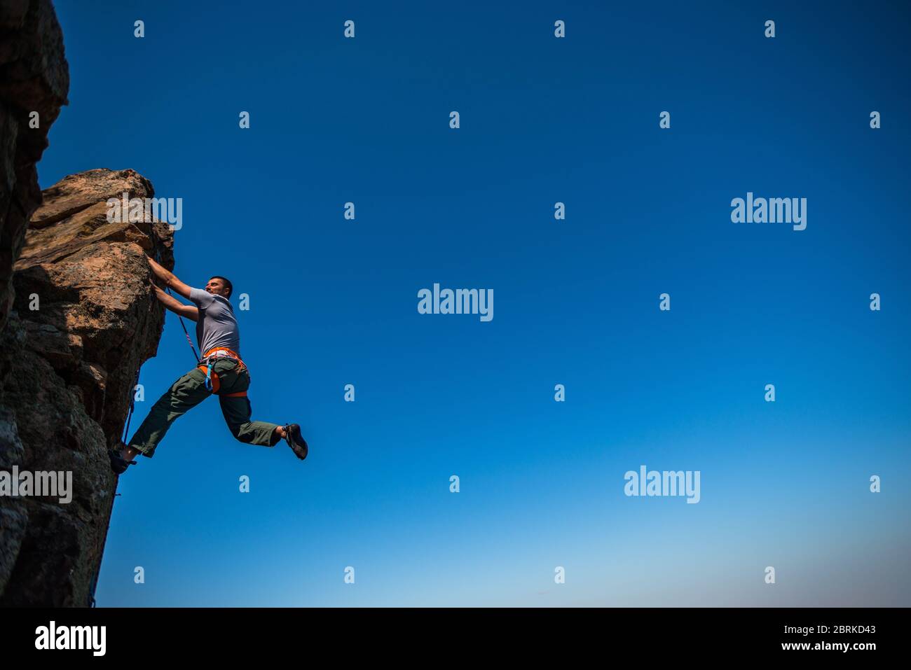Strong happy male climber practicing climbing on rock wall Stock Photo ...