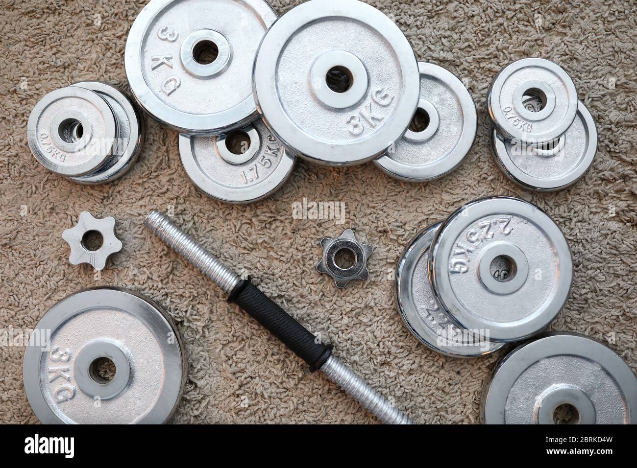 Pile of shiny chrome dumbbells disks lying around grip Stock Photo - Alamy