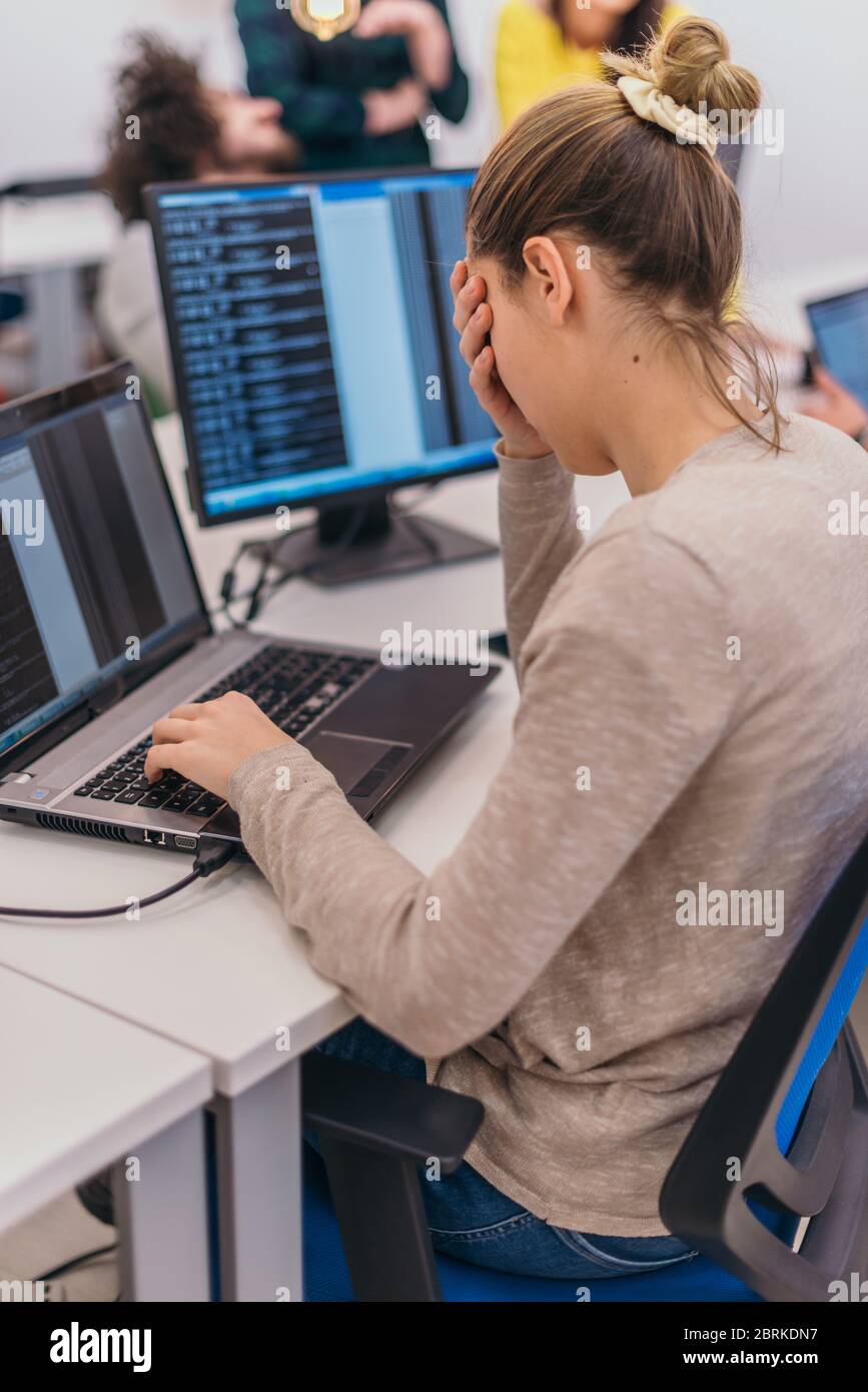 Picture from behind of a female employee sitting at her desk and ...