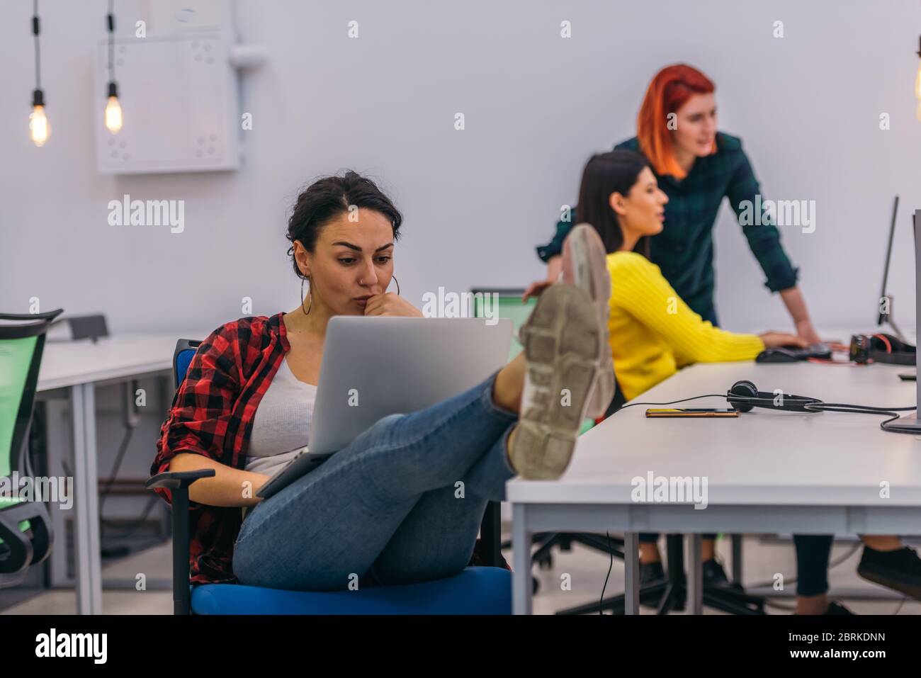 Young woman sitting at her table in the office with her legs on the ...